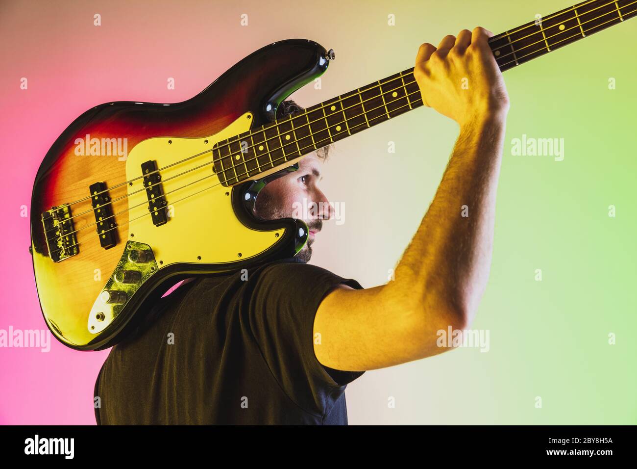 Close up young and joyful caucasian musician playing bass guitar on ...