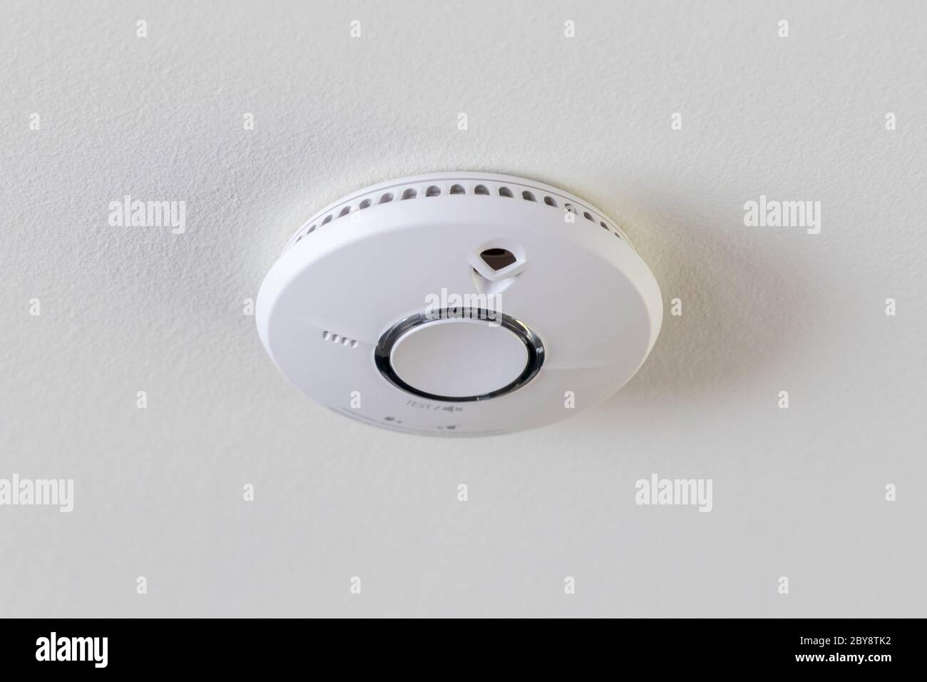 A close up portrait of a smoke detector hanging on a ceiling for safety ...
