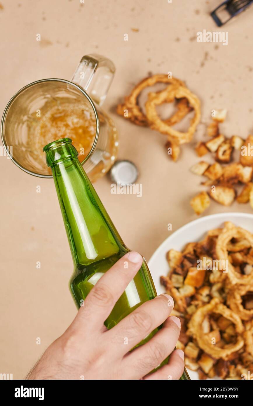 Drinking beer after work. Table full of beer snacks. Pouring bottle of ...