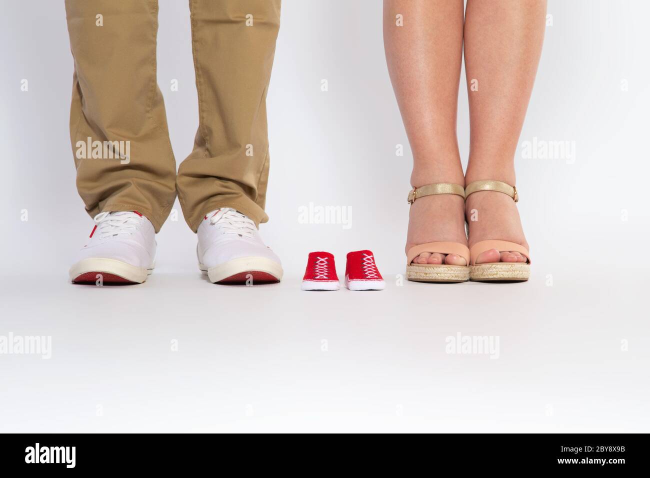 Two pairs of feet from the parents and shoes from an unborn baby ...