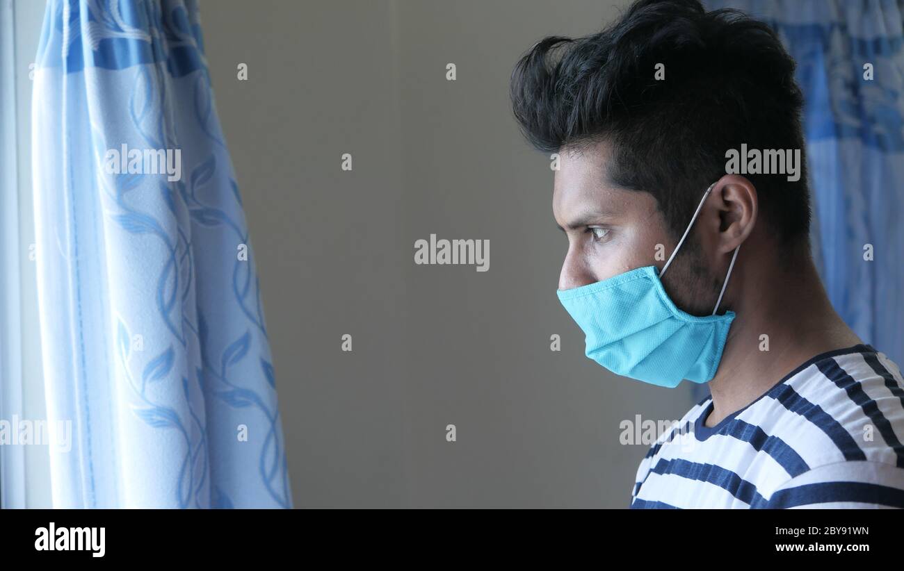 A young asian man mask on his face looking through window Stock Photo ...