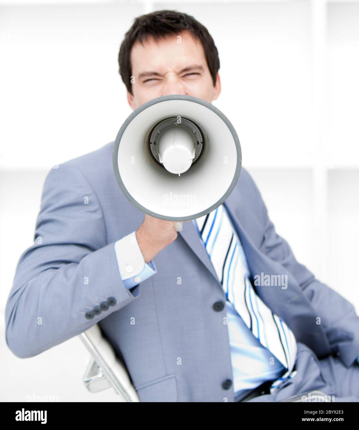 Furious young businessman yelling through a megaphone Stock Photo - Alamy