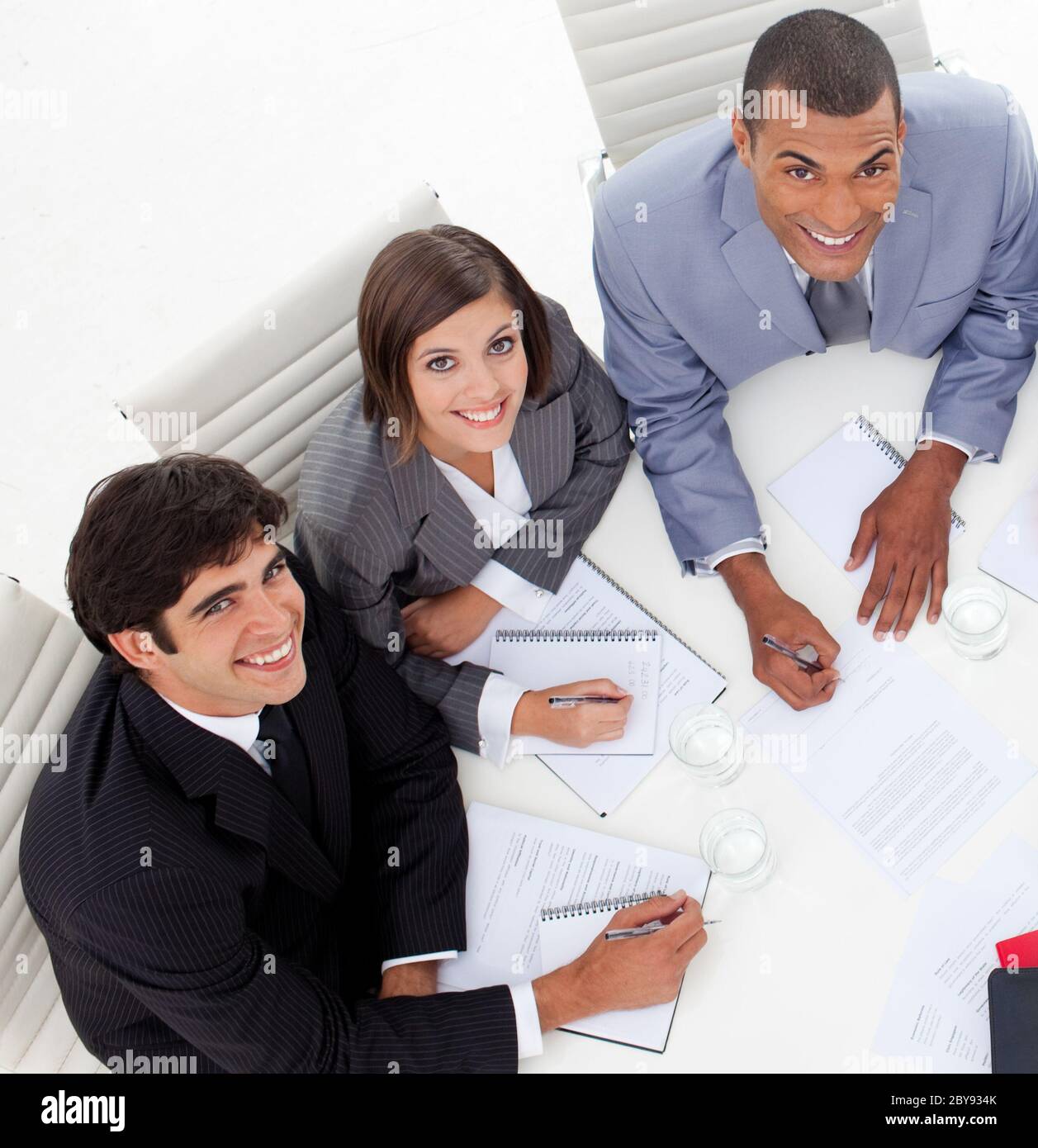 Three colleagues smiling at the camera in a meeting Stock Photo - Alamy