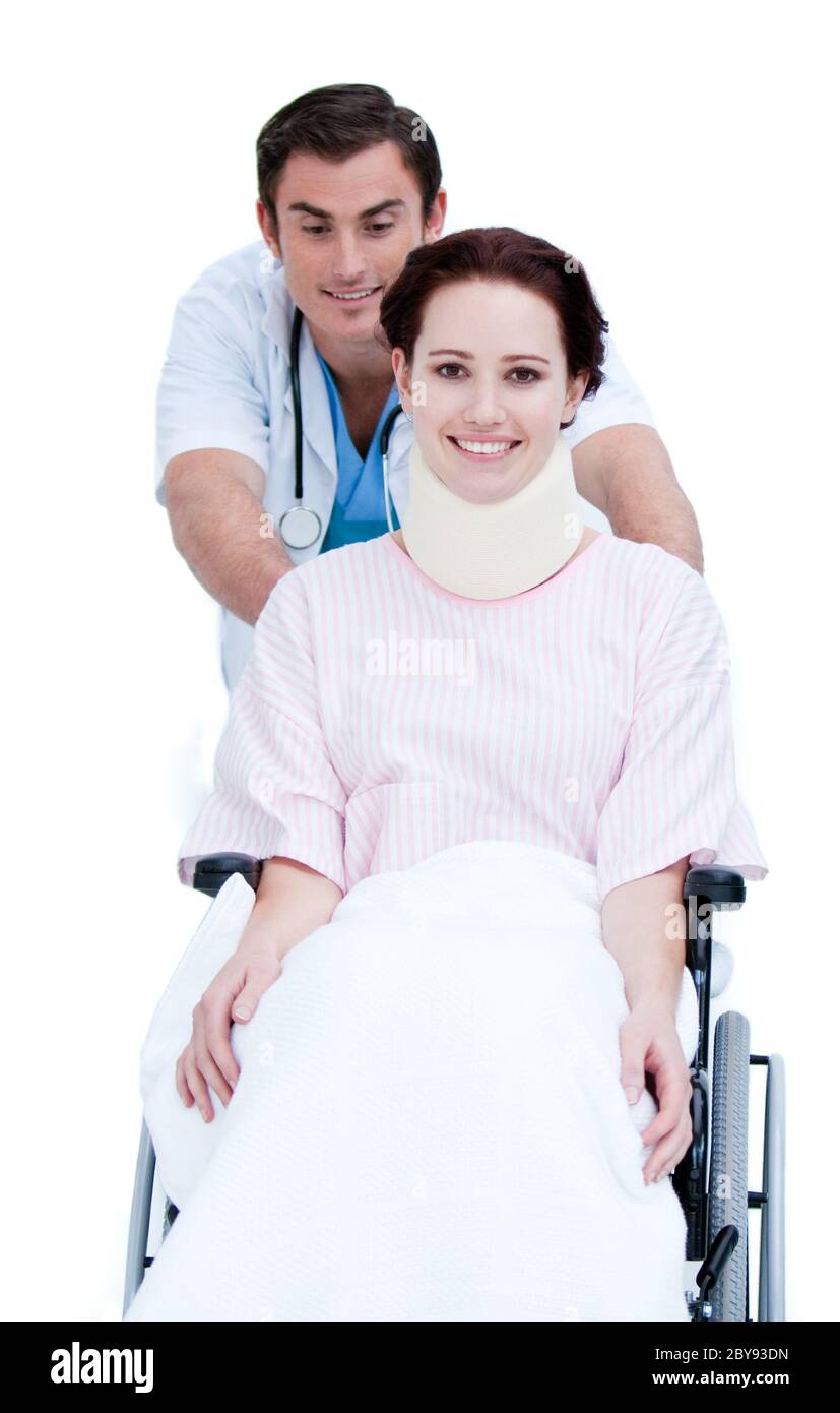 Attractive male doctor carrying a patient in a wheelchair against a ...