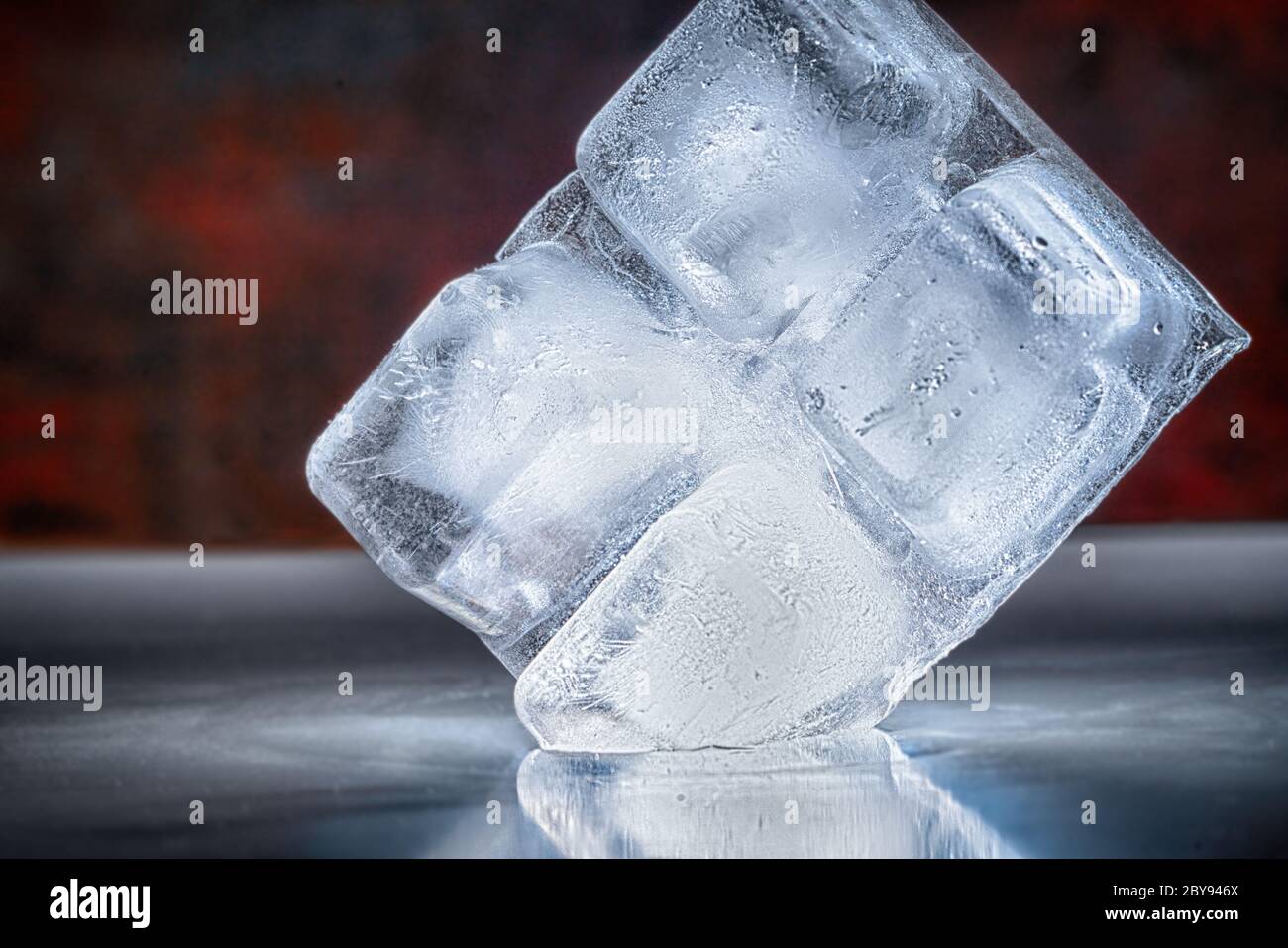 Four ice cubes in a block placed on edge balancing on the corner on a ...