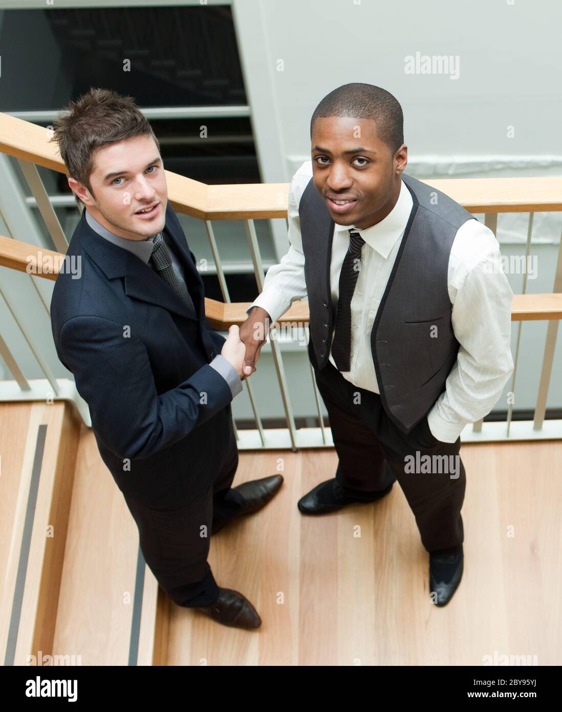Two businessmen shaking hands on stairs and smiling at the camera Stock ...