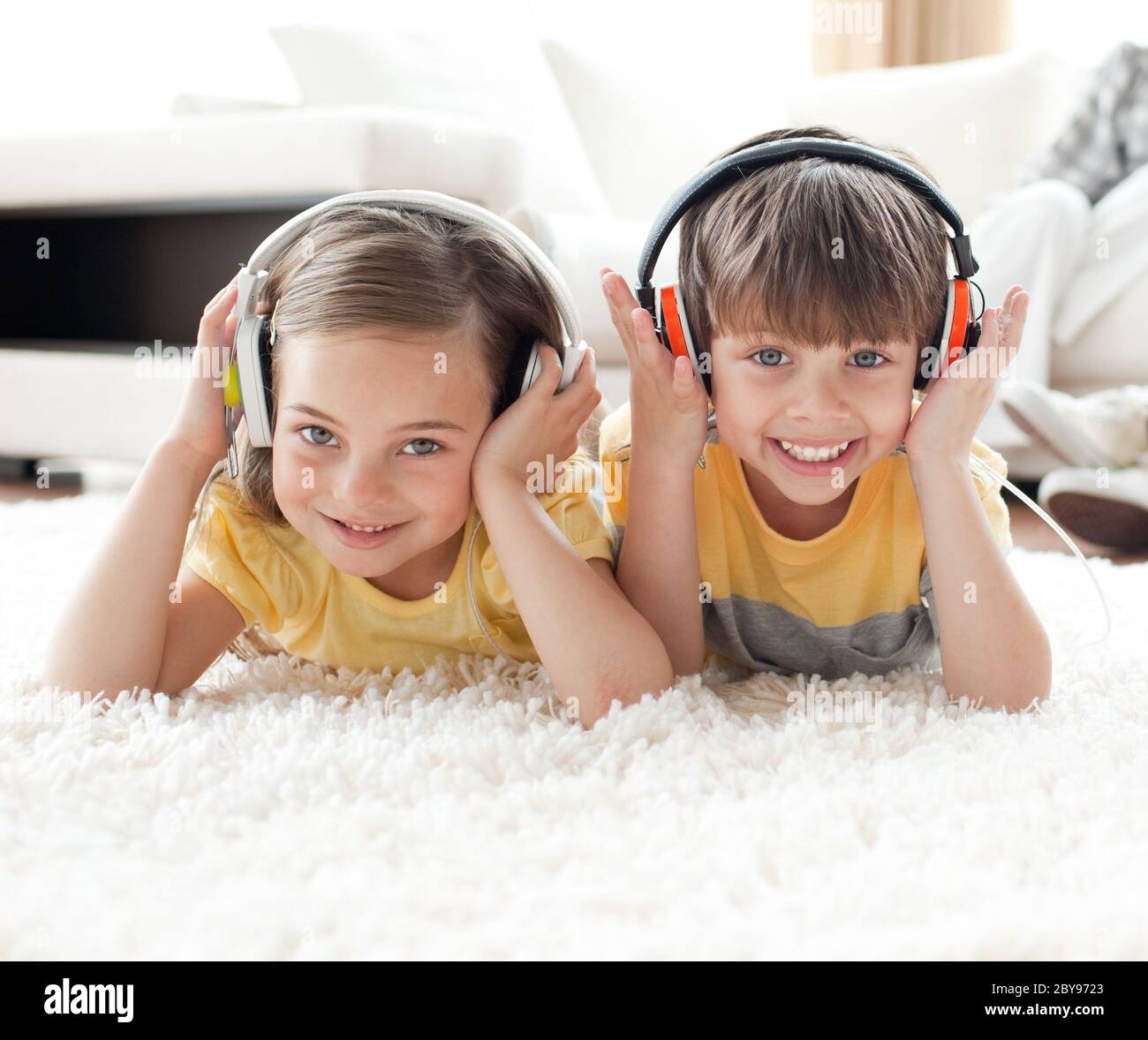 Smiling siblings listening music with headphones Stock Photo - Alamy