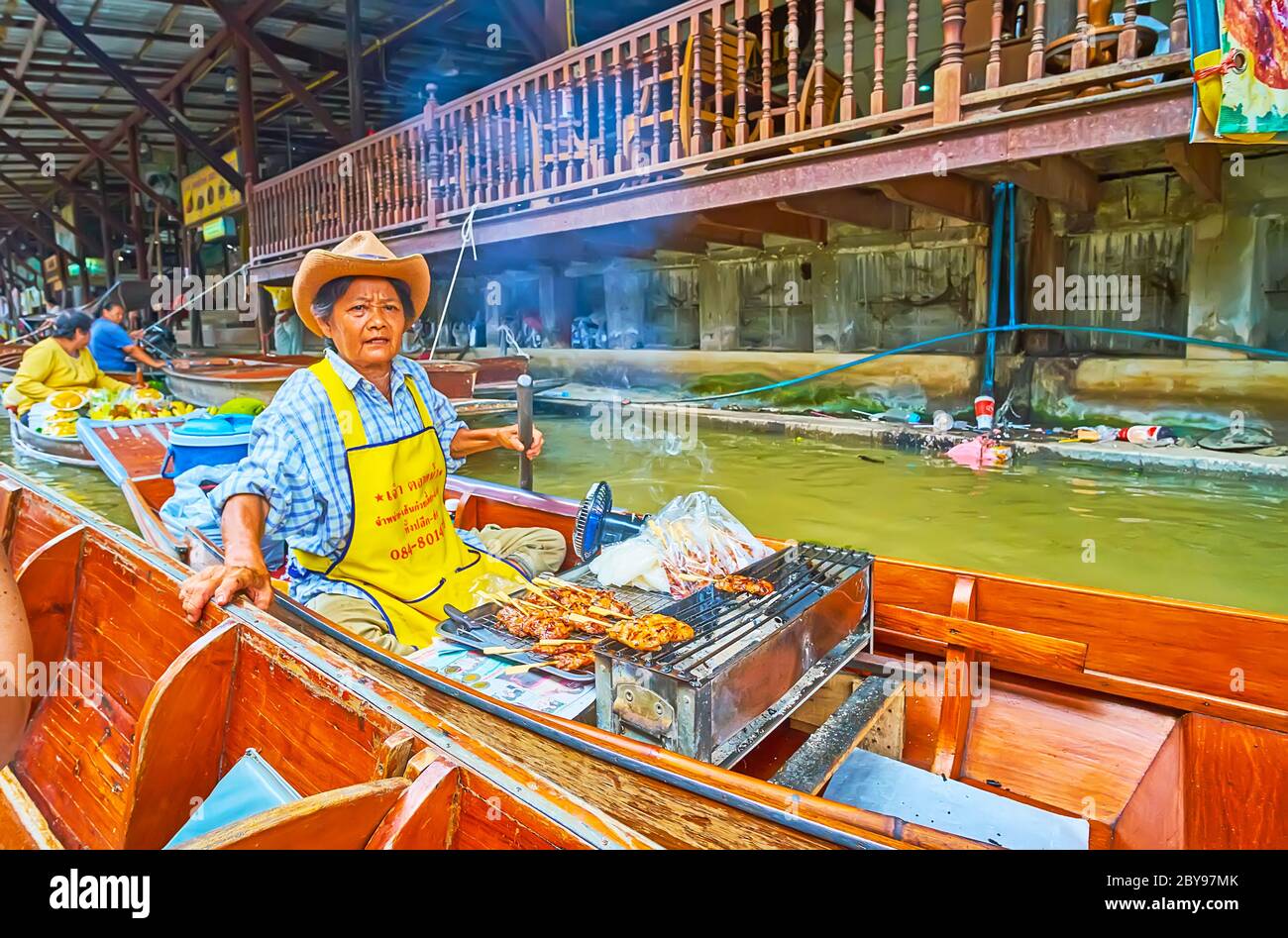DAMNOEN SADUAK, THAILAND - MAY 13, 2019: The elderly vendor sells ...
