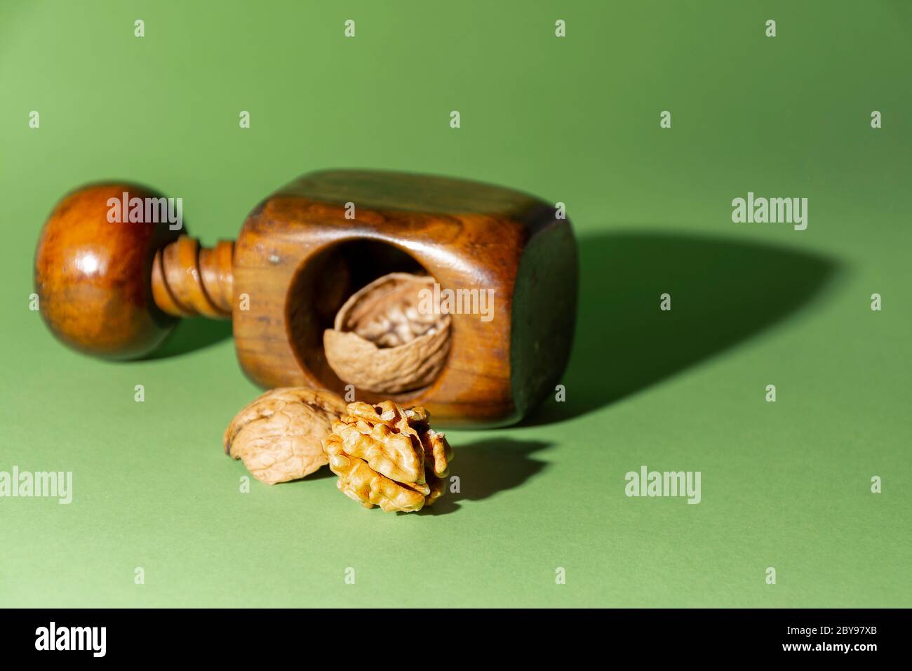 Peeled nut next to its shells and a nutcracker, on green background ...