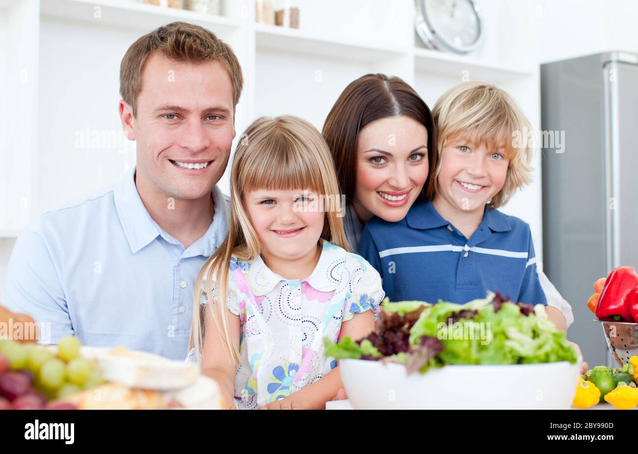 Attentive parents and their children cooking together in the kitchen ...