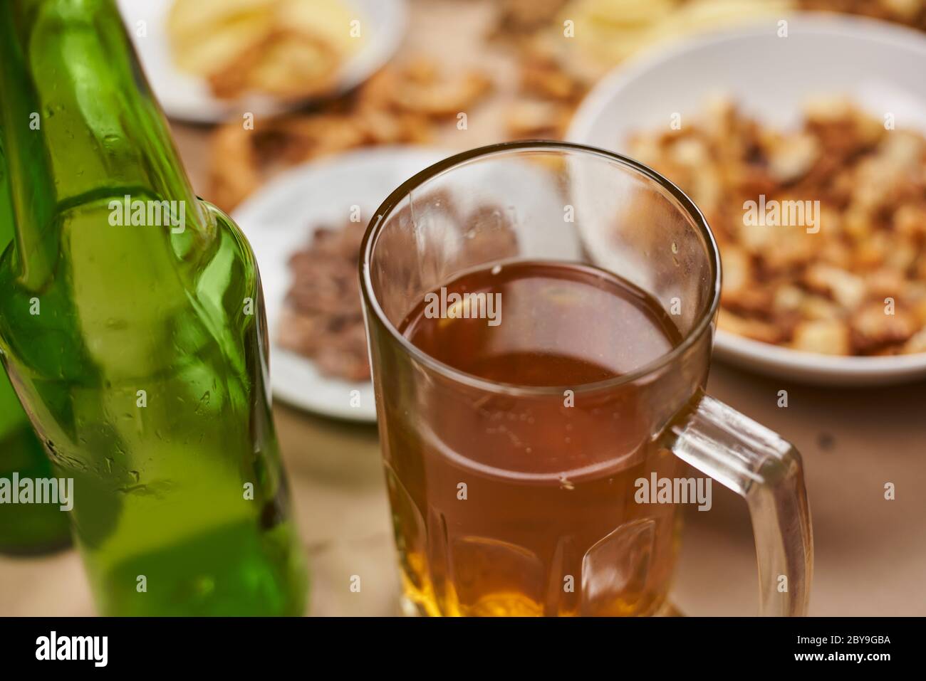 Drinking beer after work. Table full of beer snacks. Pouring bottle of ...