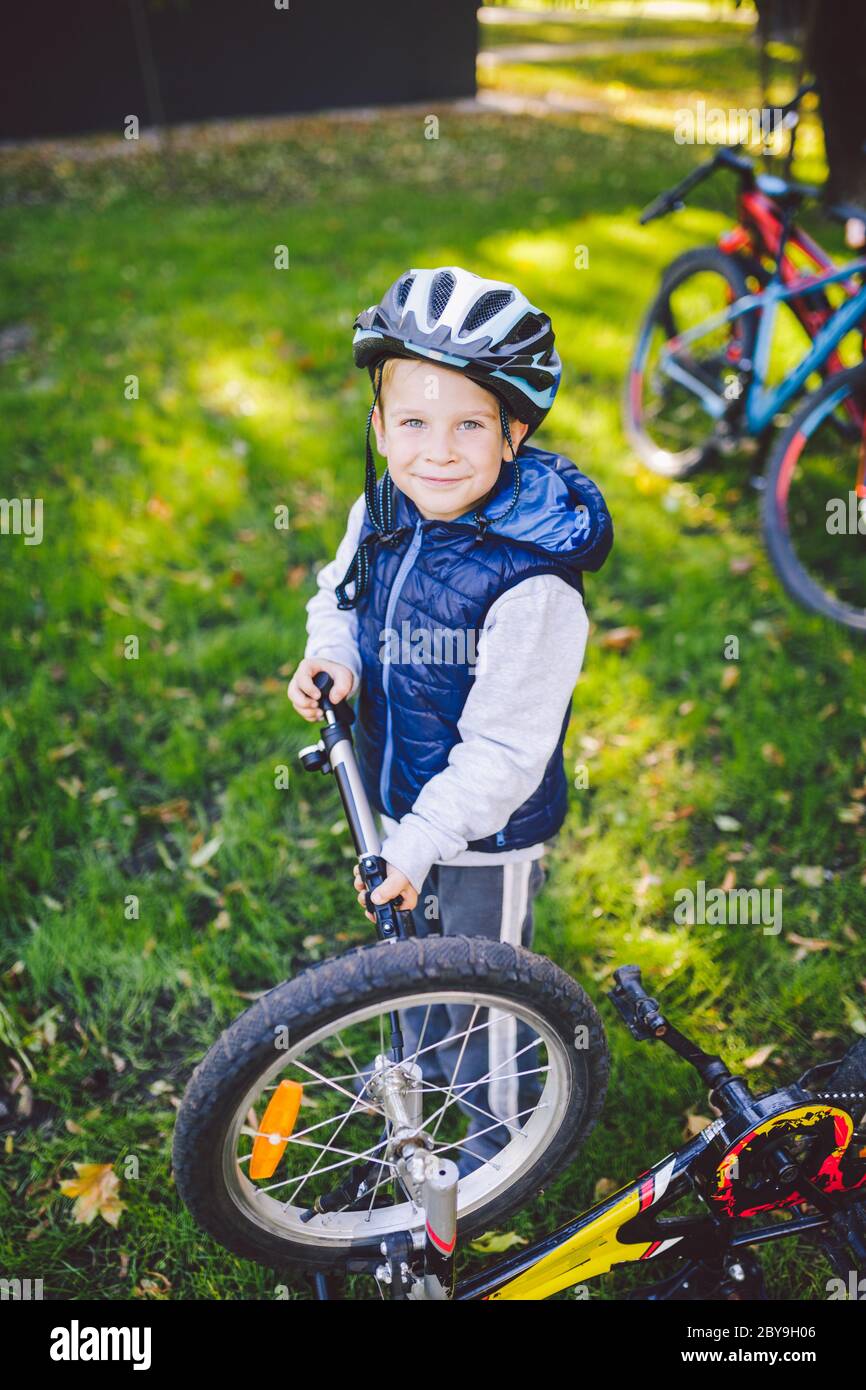 Caucasian child boy in a helmet learns to repair his bike. Child ...