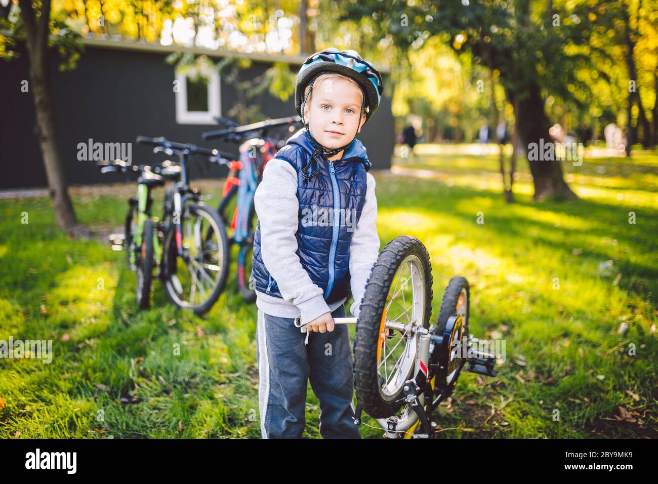 Caucasian child boy in a helmet learns to repair his bike. Child ...