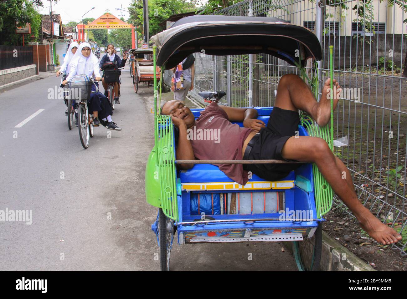 JOGJAKARTA, INDONESIA - JUNE 12, 2013: Rickshaw driver sleeping on the job in the streets of ...