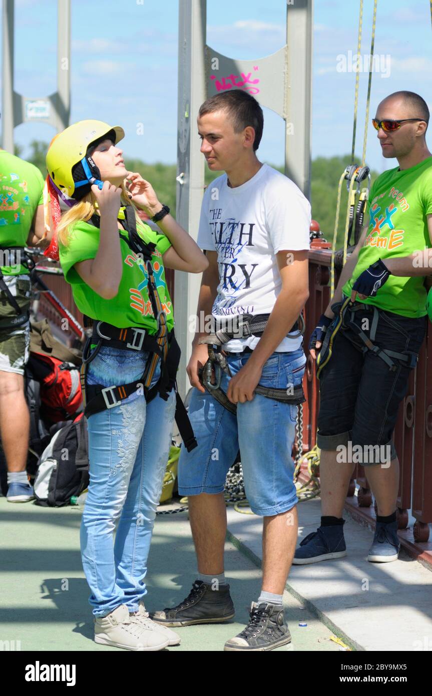 Bungee jumping. Worker attaching rigging to the young girl before ...