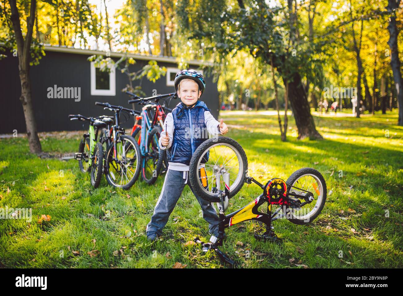 Caucasian child boy in a helmet learns to repair his bike. Child ...