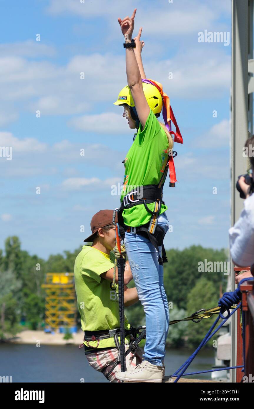 Bungee jumping. Girl standing on the bridge railing hands up ready to ...