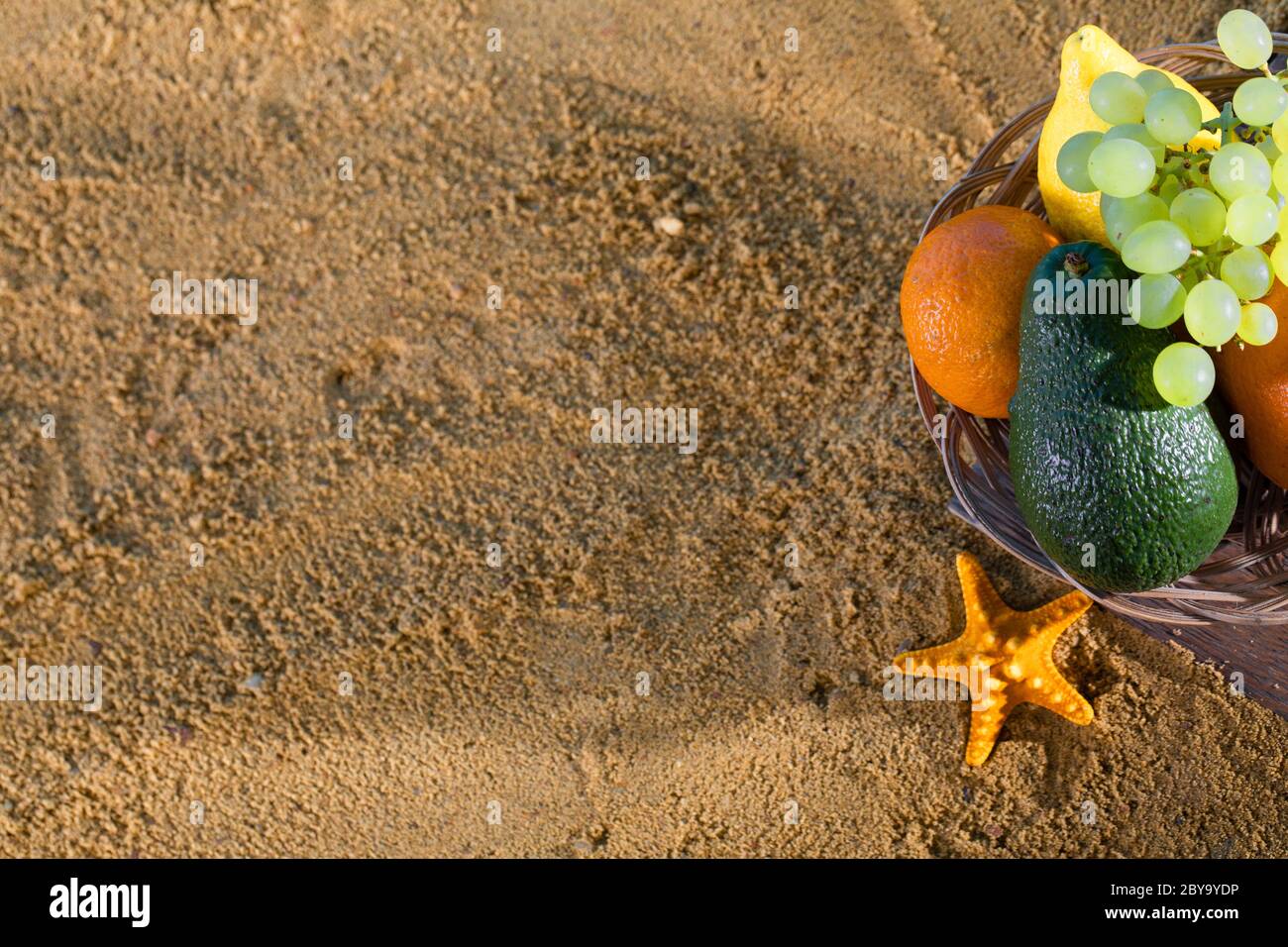 Ripe southern fruits lie in the basket. Sea shore of a sandy beach ...