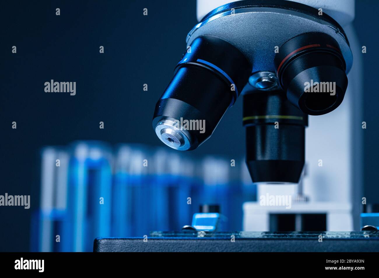 Close up of laboratory microscope with set of test tubes with blue ...
