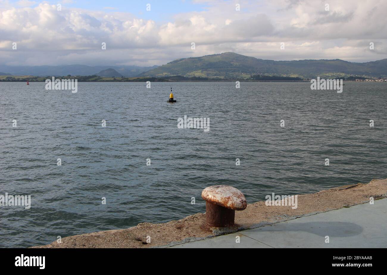 Rusted bollard on the edge of the pavement Santander bay with a yellow ...