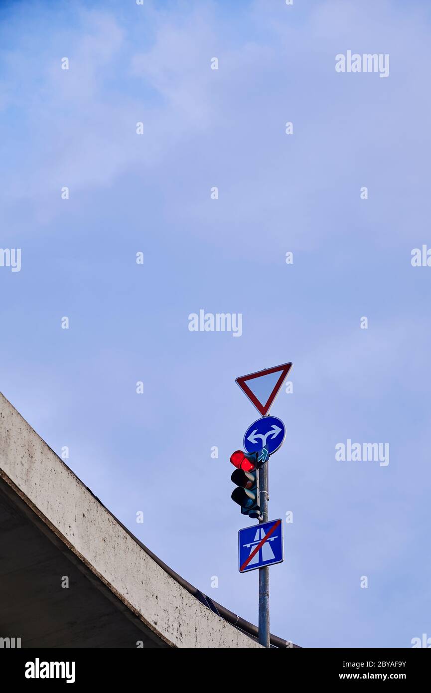 Bottom view of a red traffic light and various traffic signs at an ...