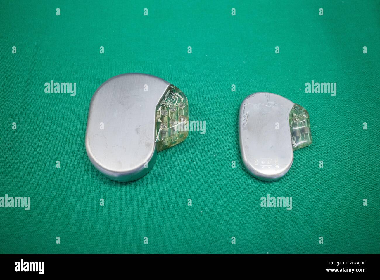 a pacemaker lies directly next to a defibrillator on a green surgical ...