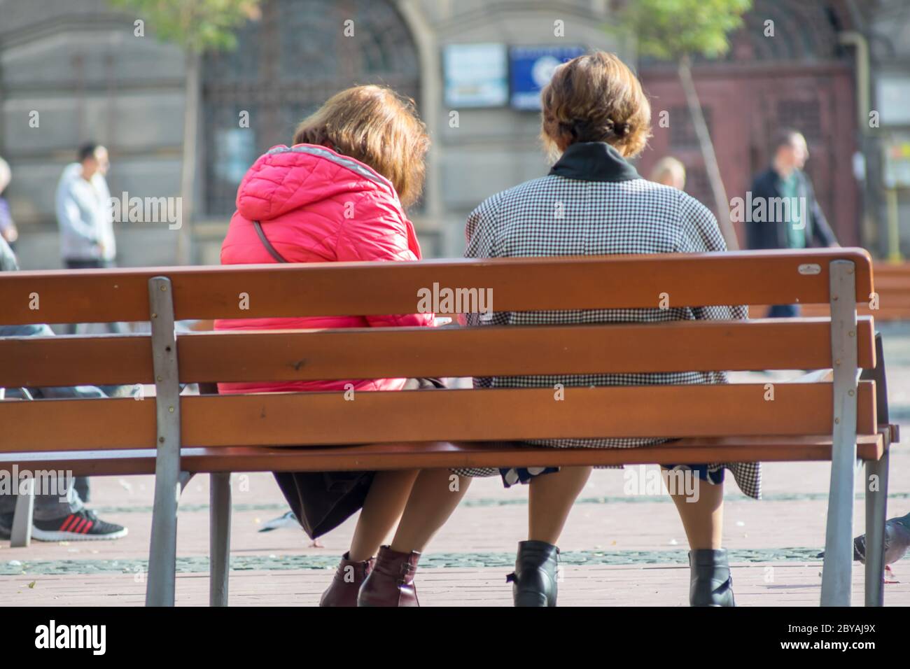 Two women sitting on a bench. Real people Stock Photo - Alamy