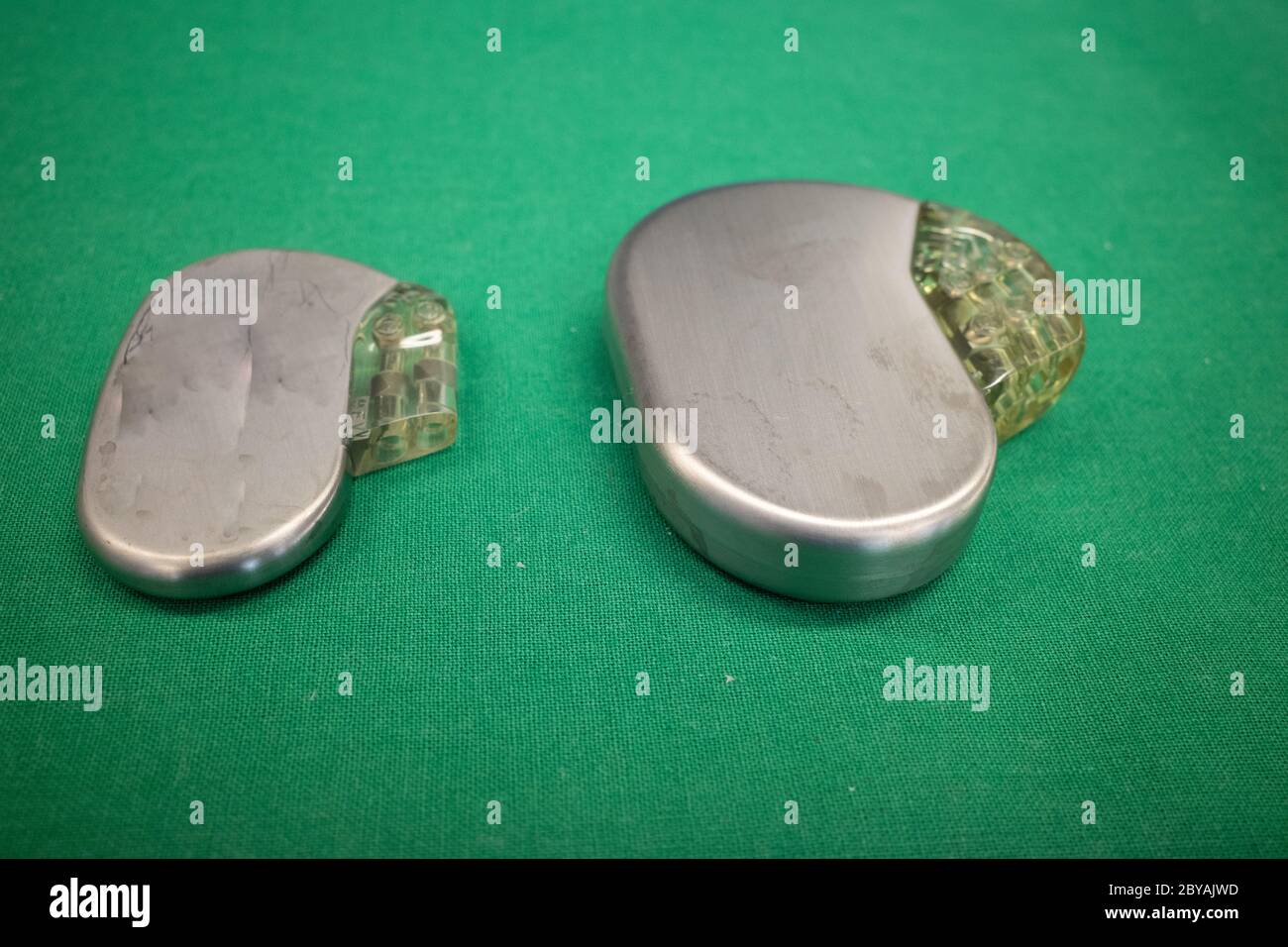 a pacemaker lies directly next to a defibrillator on a green surgical ...