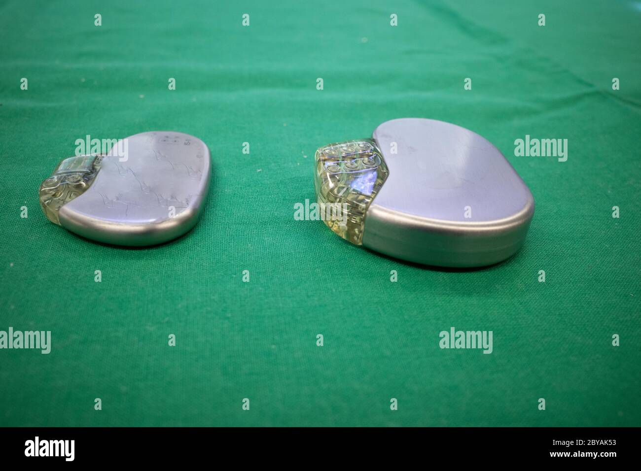 a pacemaker lies directly next to a defibrillator on a green surgical ...