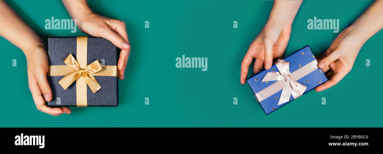 Web banner with women's hands holding a gift boxes with gifts or surprises on a green background ...