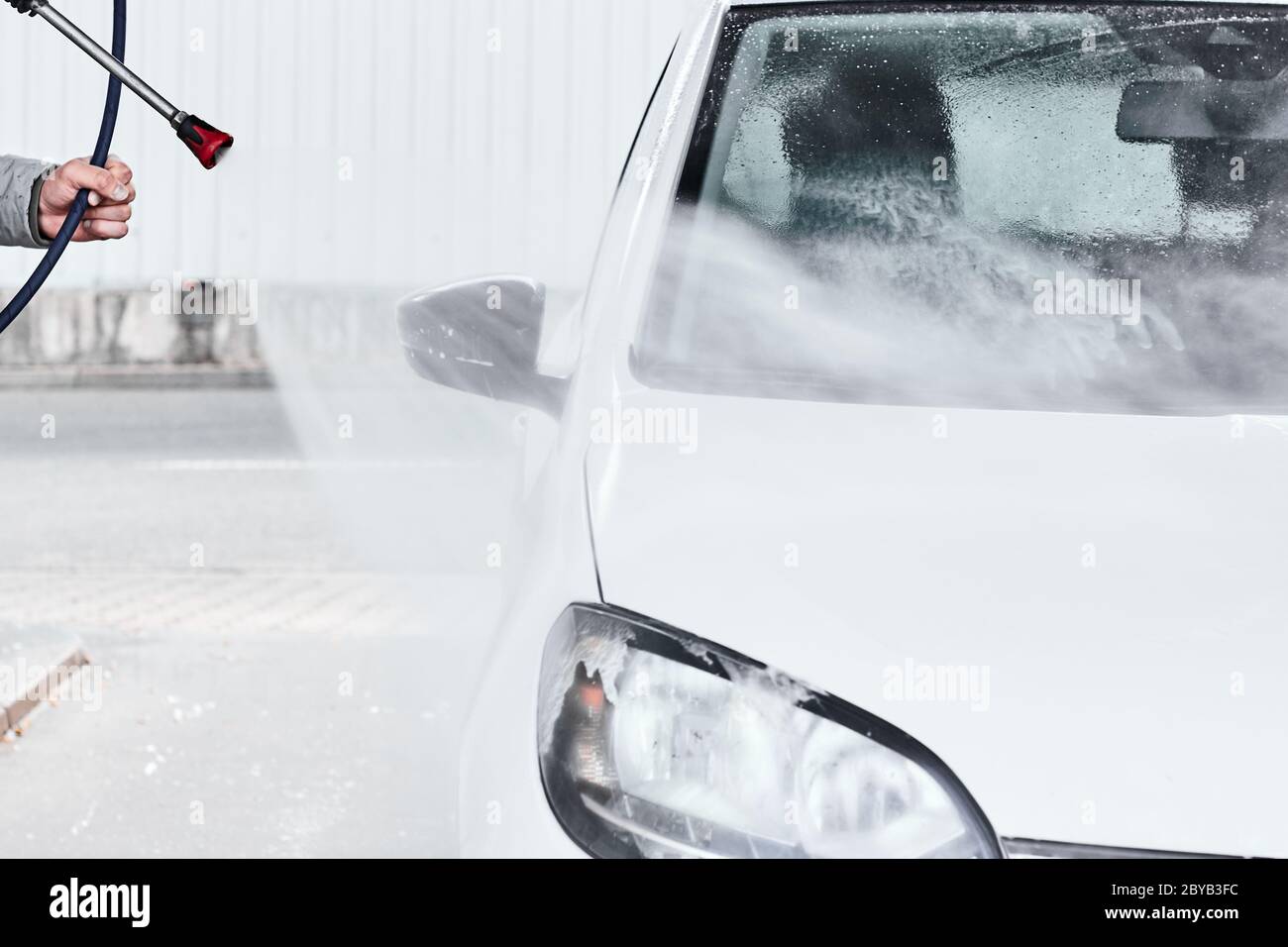 Close up mans hand washing a white car using high pressure water. Car ...