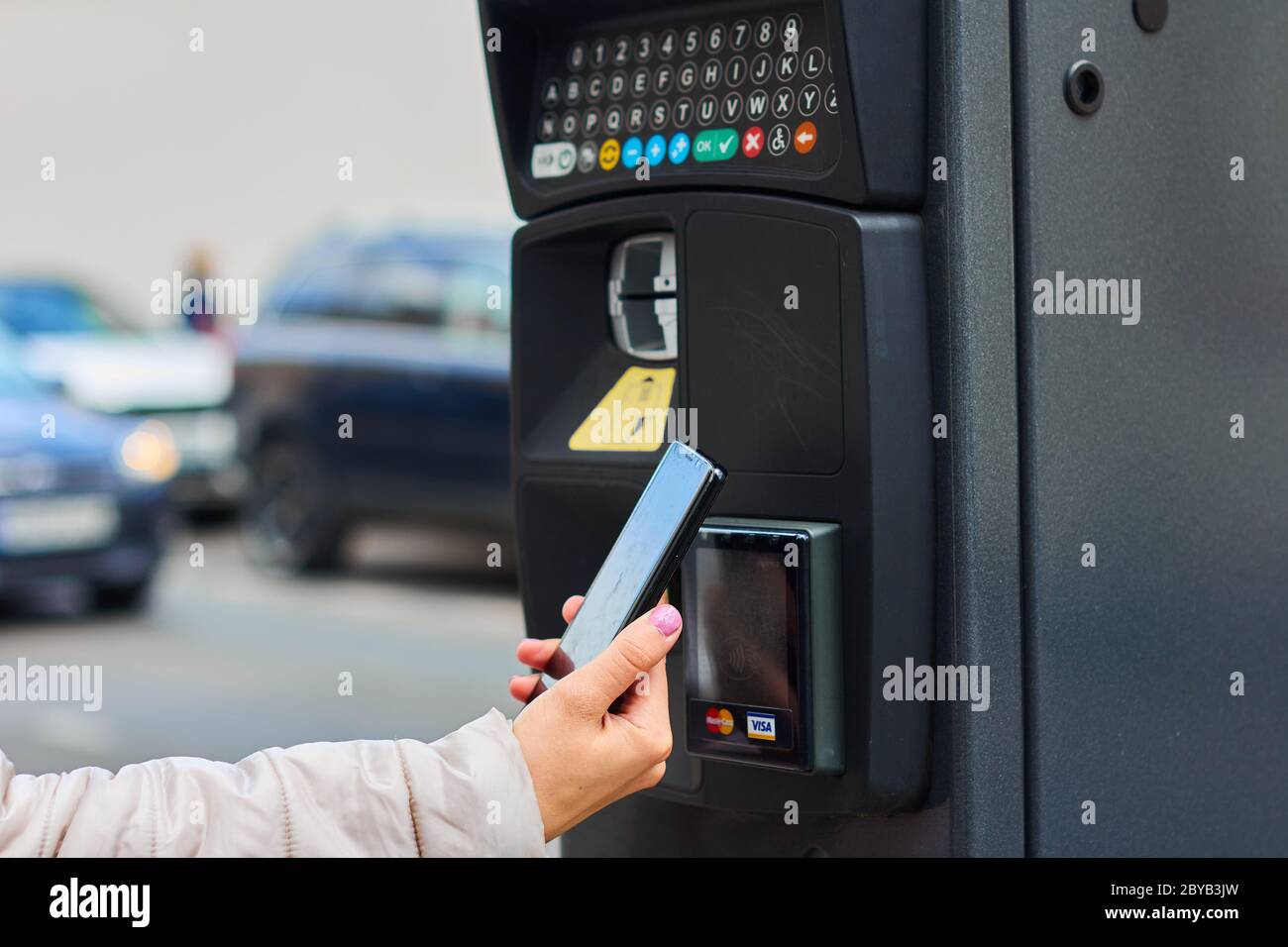 Young women paying for the parking using NFC in her smartphone ...