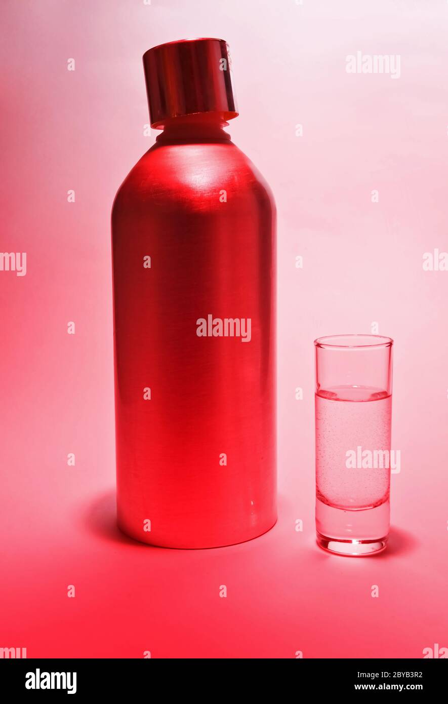 Aluminum bottle and a glass of vodka in pink light Stock Photo - Alamy