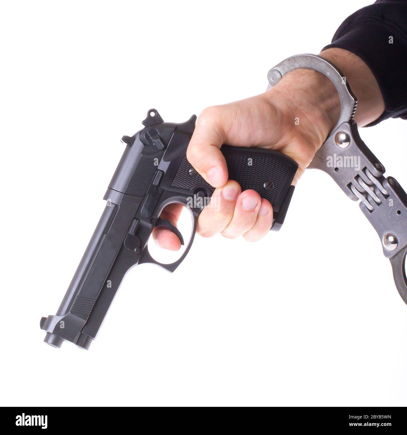 Pistol in hand with handcuffs Stock Photo - Alamy
