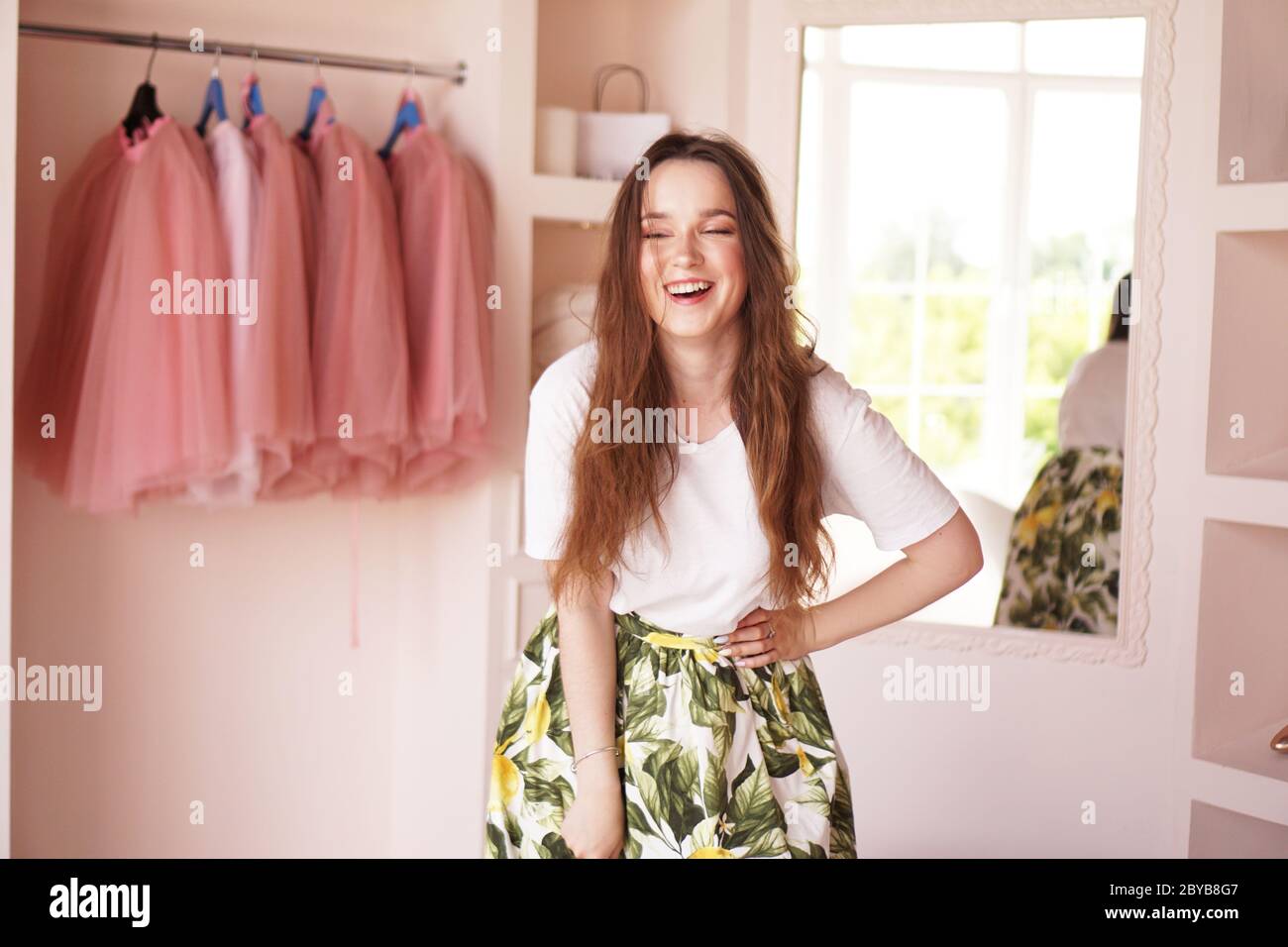Happy young woman dressing up. Dressing room in pink colors. The ...