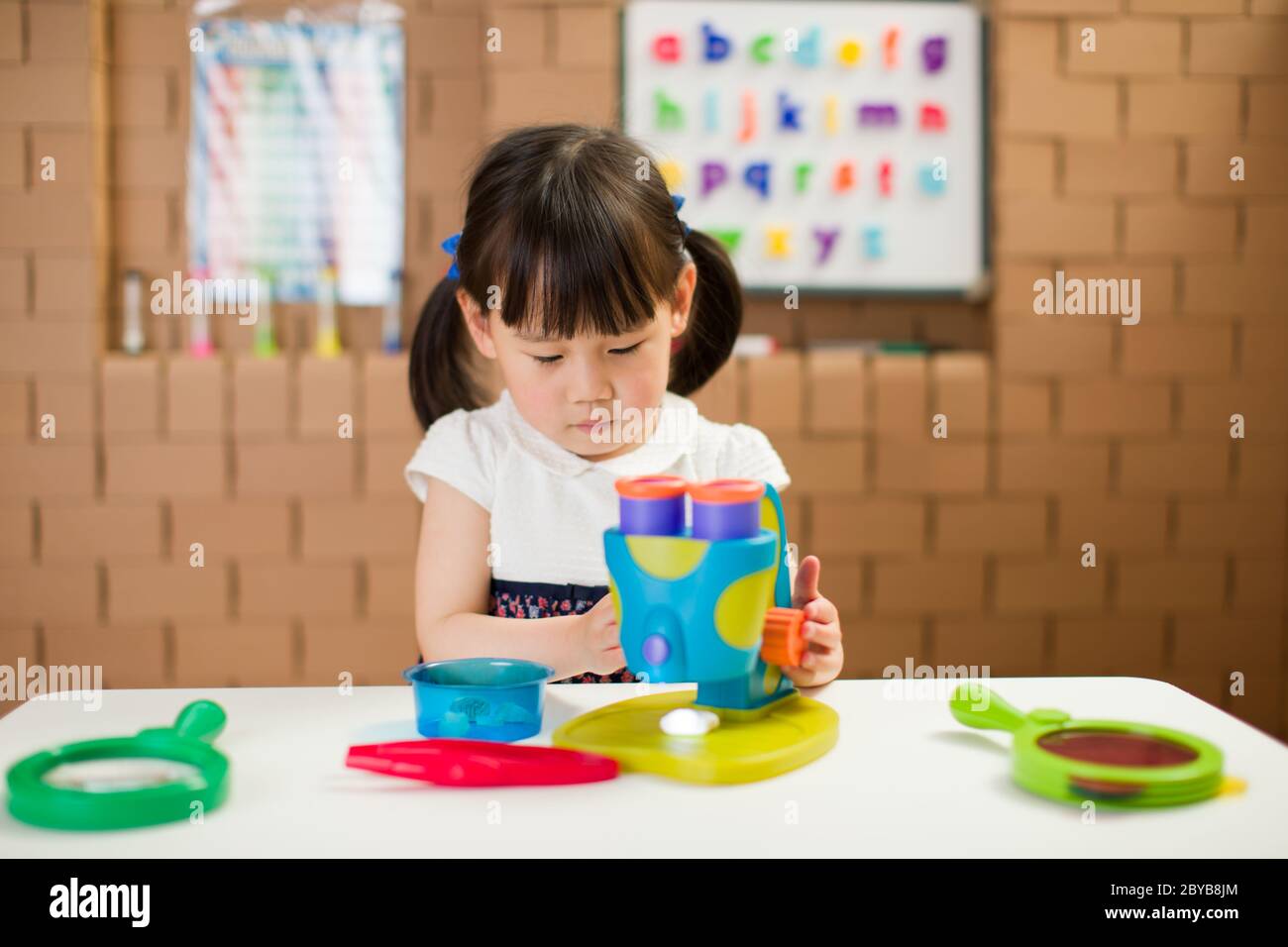 toddler girl play microscope for homeschooling Stock Photo - Alamy