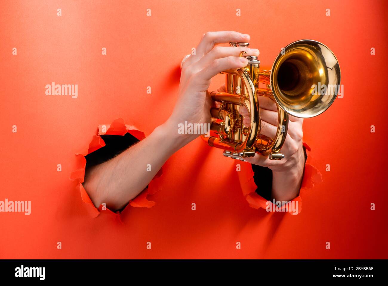 Hands playing trumpet torn holes in red paper background Stock Photo ...
