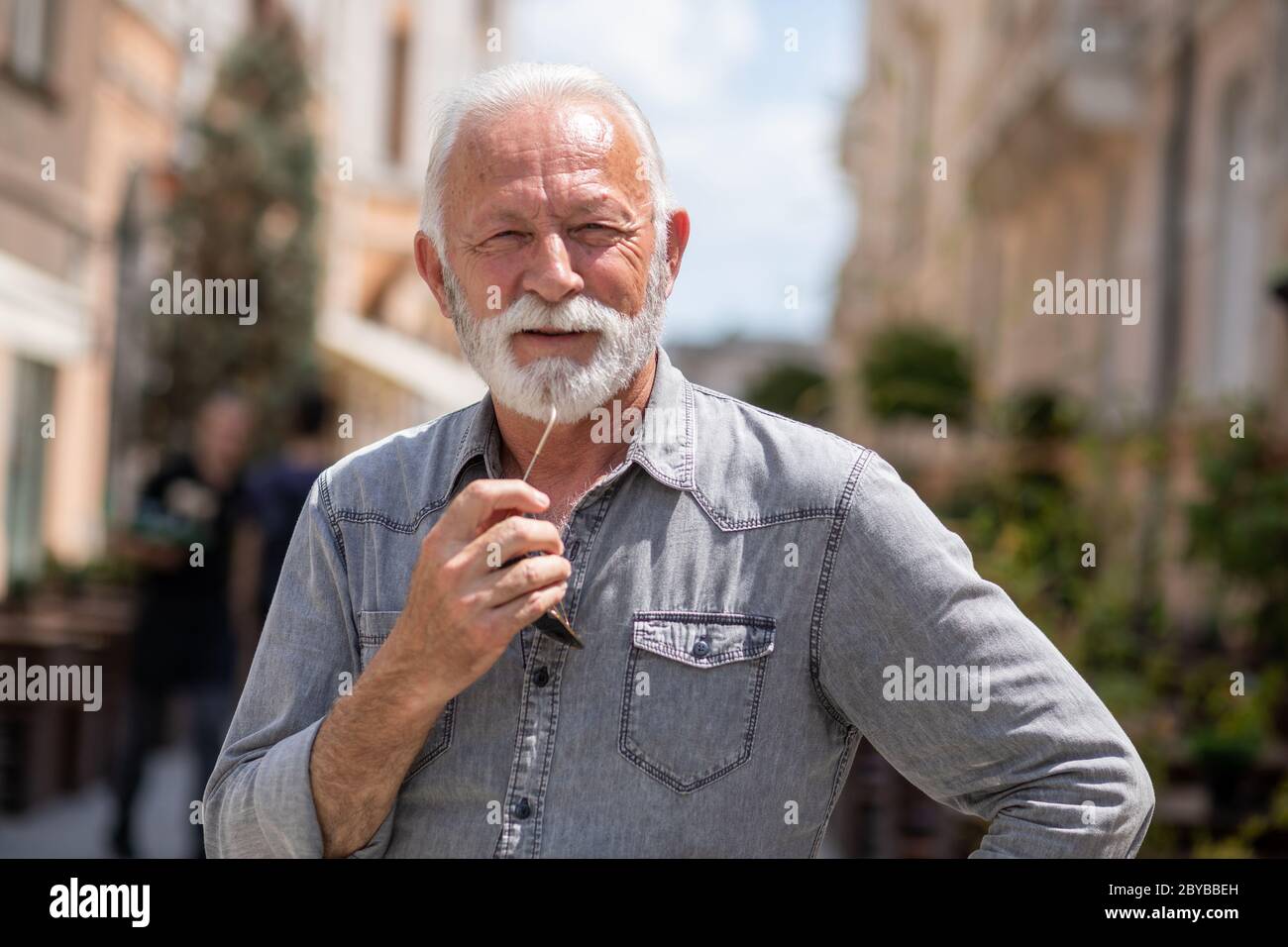Happy rich old man with beard on street posing and smiling, portrait ...