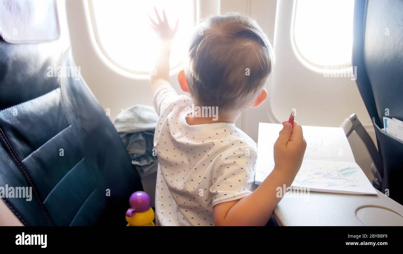 Cute little boy looking out of the window in airplane during flight ...