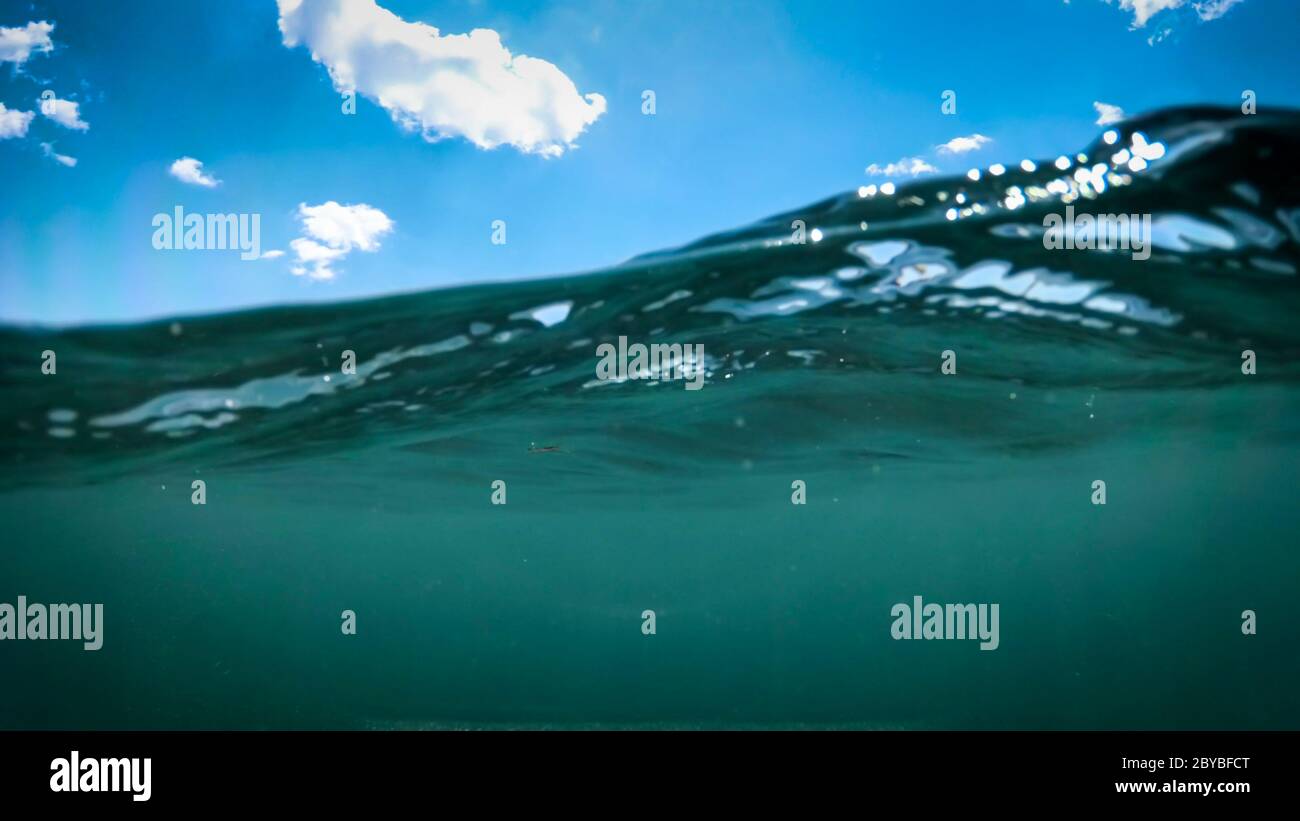 Underwater image of clear blue sky and rolling sea wave Stock Photo - Alamy