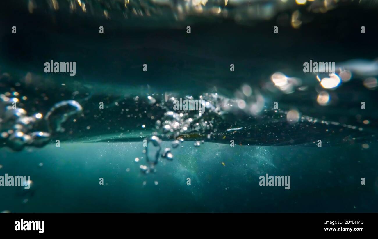 Underwater image of air bubbles floating up to the surface in sea water ...