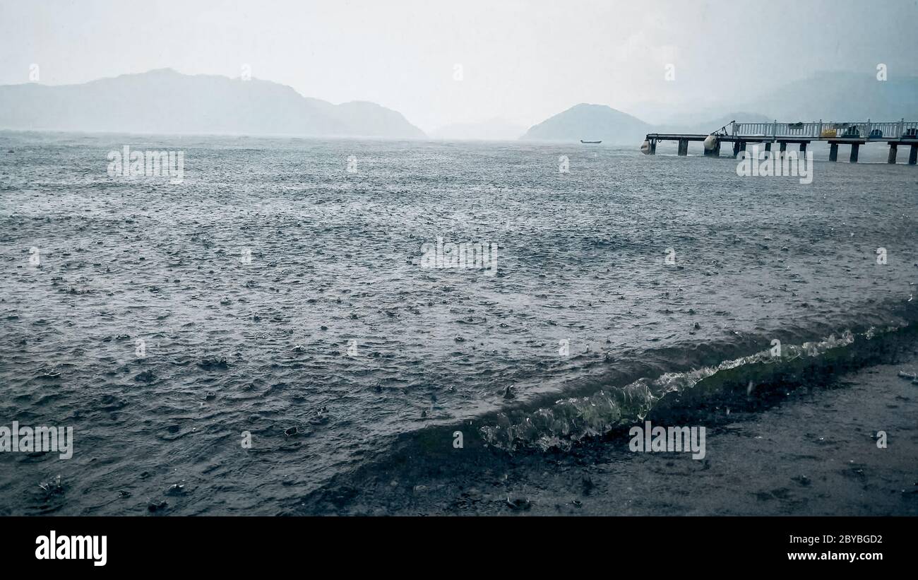 Heavy rain over the sea beach and wooden pier Stock Photo - Alamy