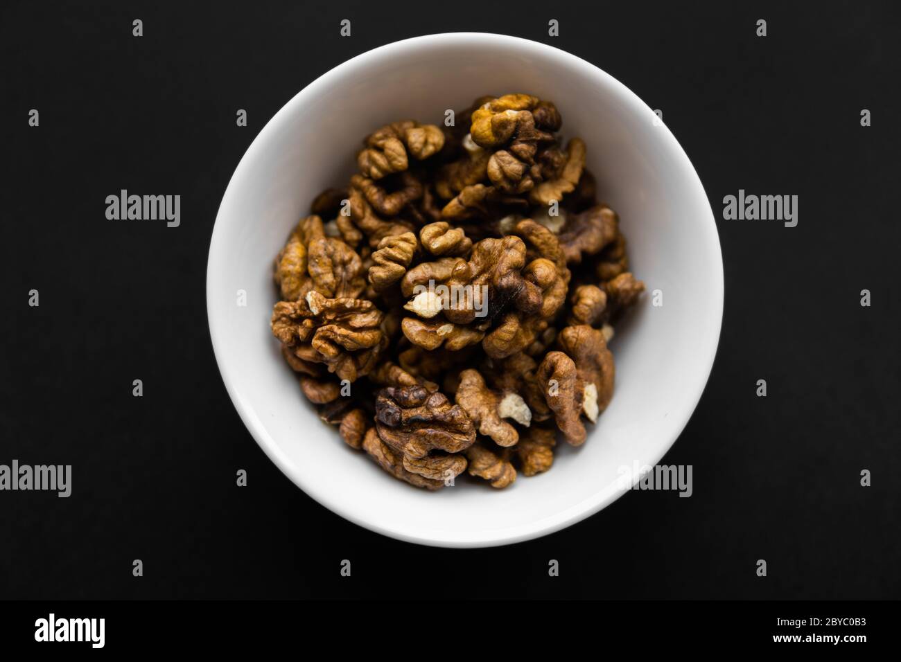 Walnut in a small plate on a black table. Walnuts is a healthy ...