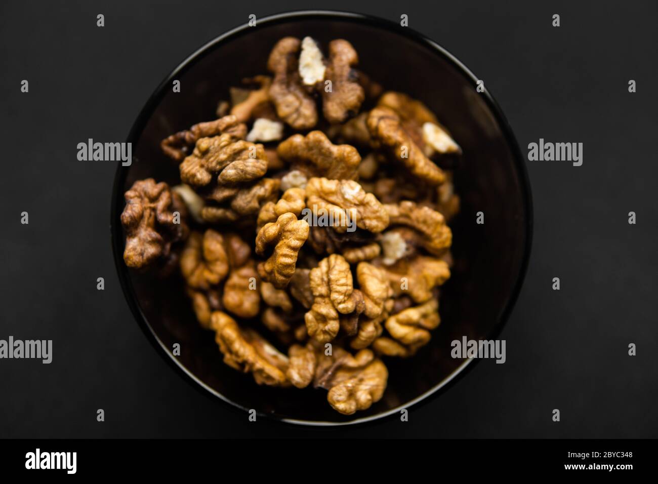 Walnut in a small plate on a black table. Walnuts is a healthy ...