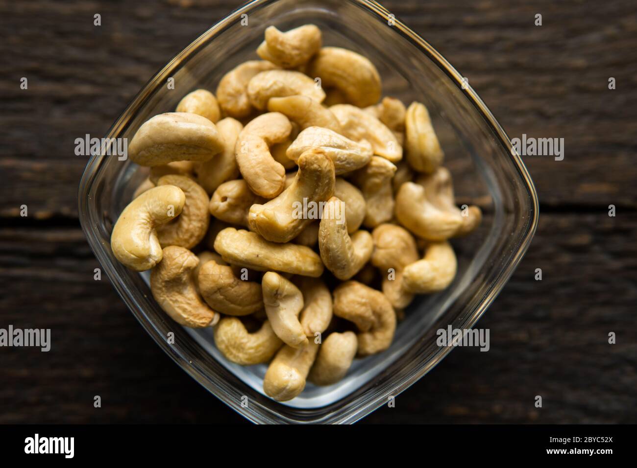 Cashew nuts in a small plate on a vintage wooden table as a background ...
