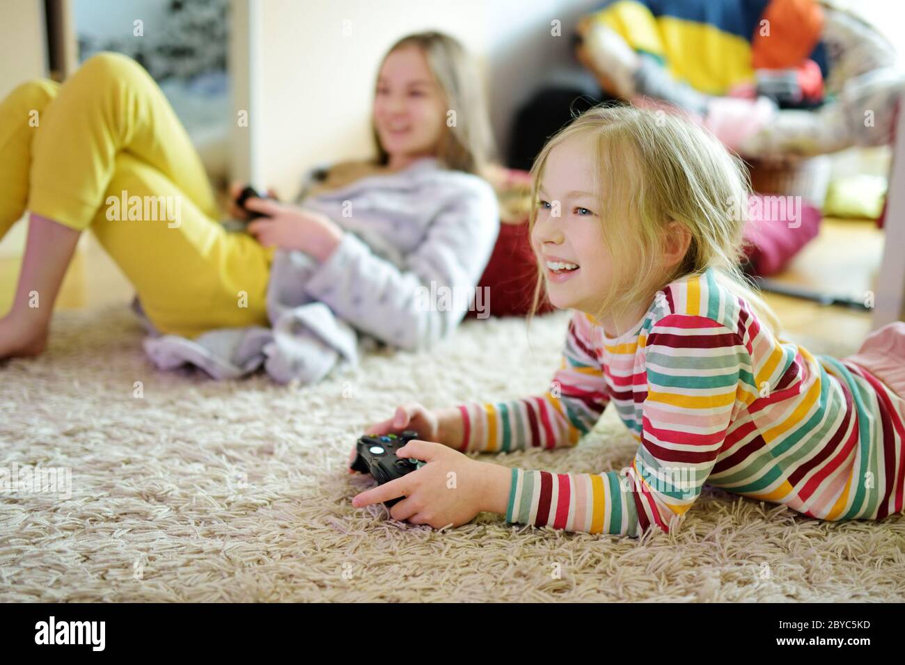 Two sisters playing video games at home. Children having fun together ...