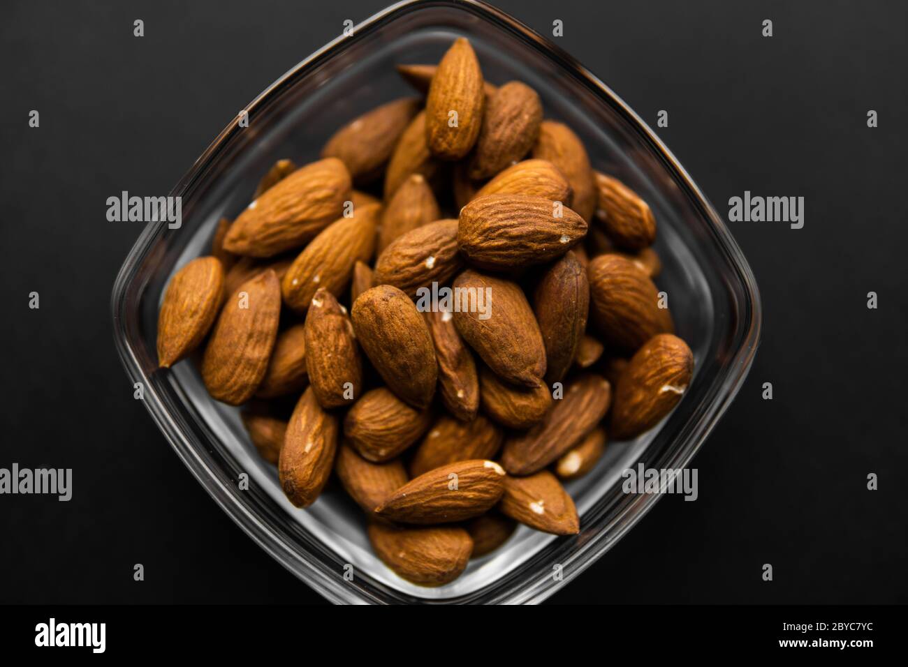 Almonds in a small plate on a black table. Almond is a healthy ...