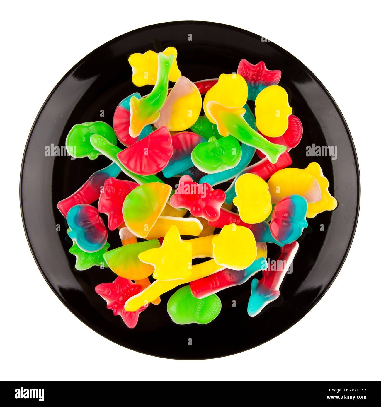 Colorful candies in many different shapes isolated on a black plate ...