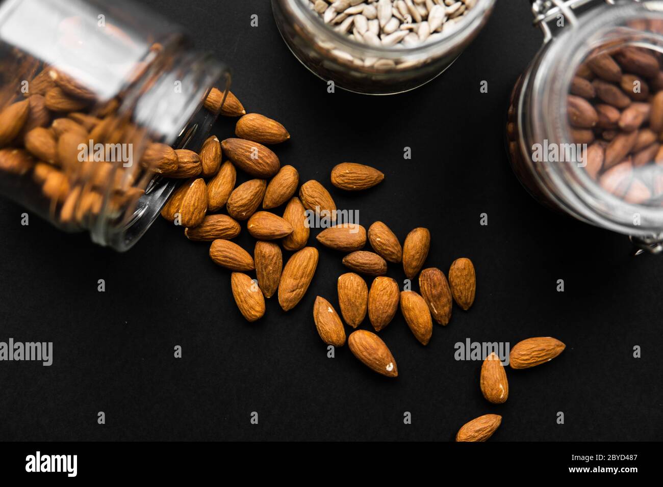 Almond scattered on the black table from a jar. Walnut is a healthy ...