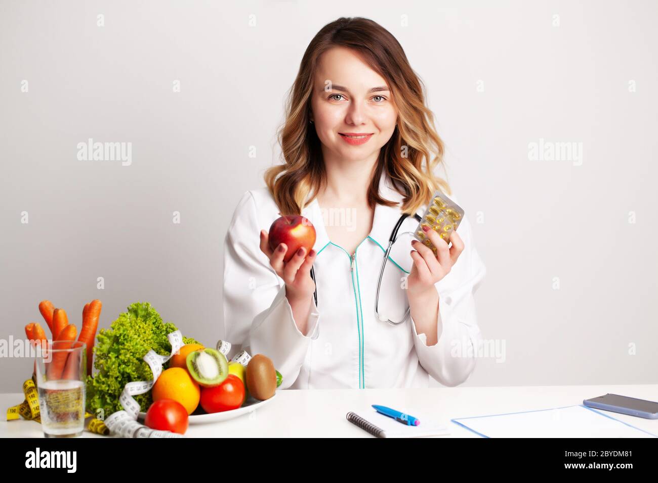 Young dietitian doctor at consulting room at table with fresh ...